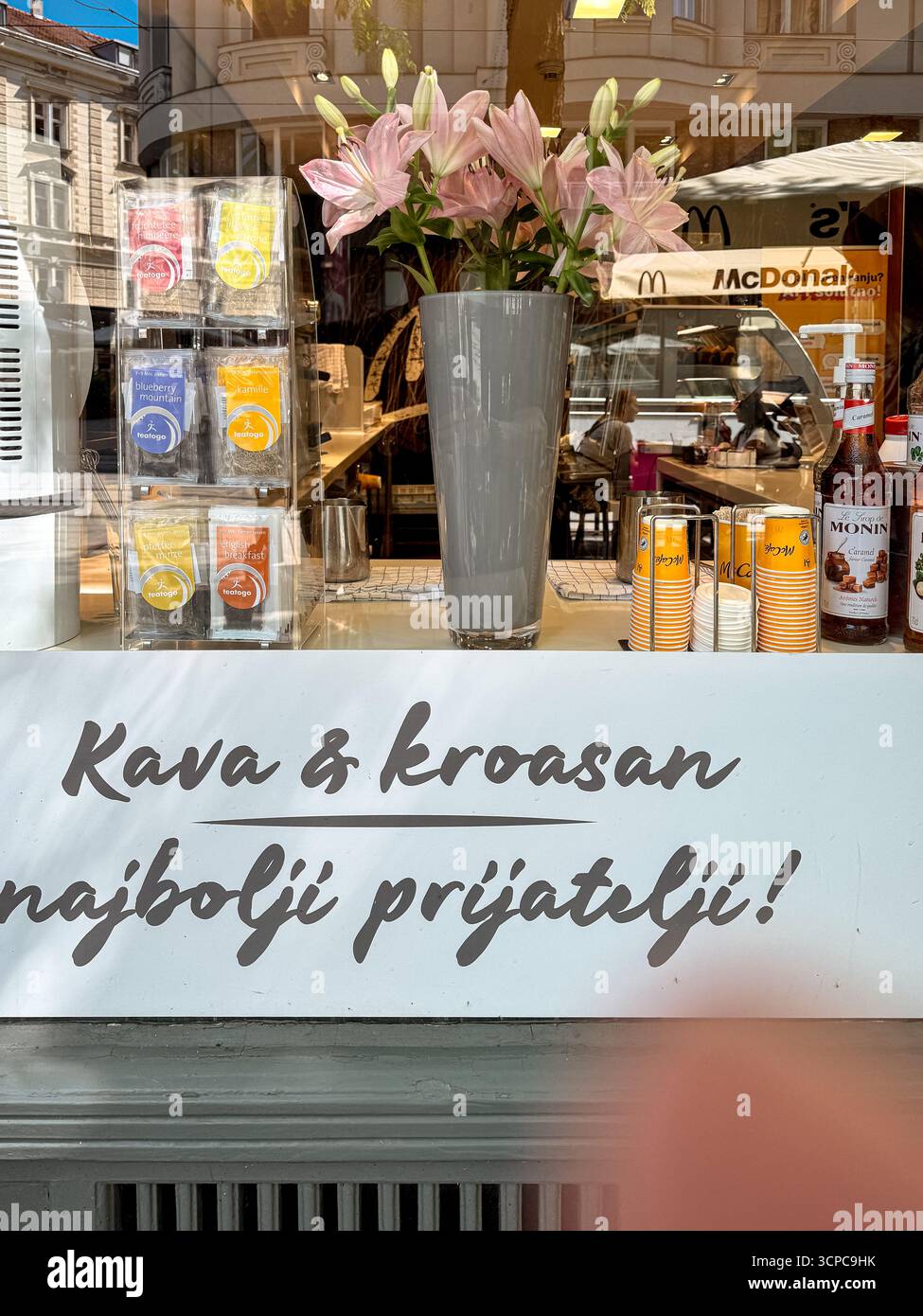 A café window display in Zagreb with flowers, coffee, and pastries and ...