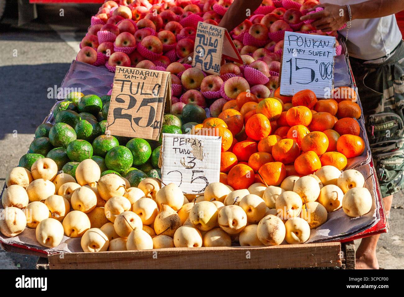 Oranges, apples, and pears sold on a cart at a fruit stand in a public ...