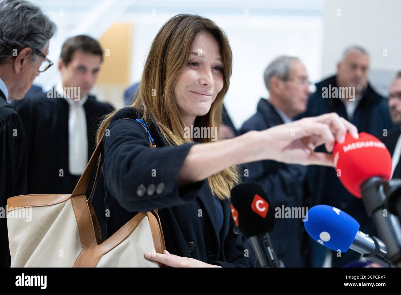 Carla Bruni grabs the windscreen of a Mediapart microphone after her ...