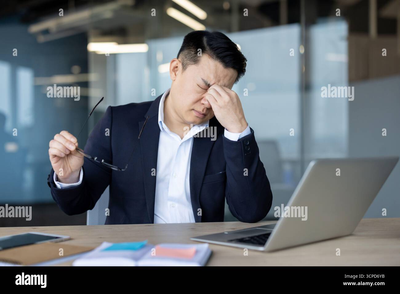 Tired young Russian man sits in the office at the workplace in front of ...