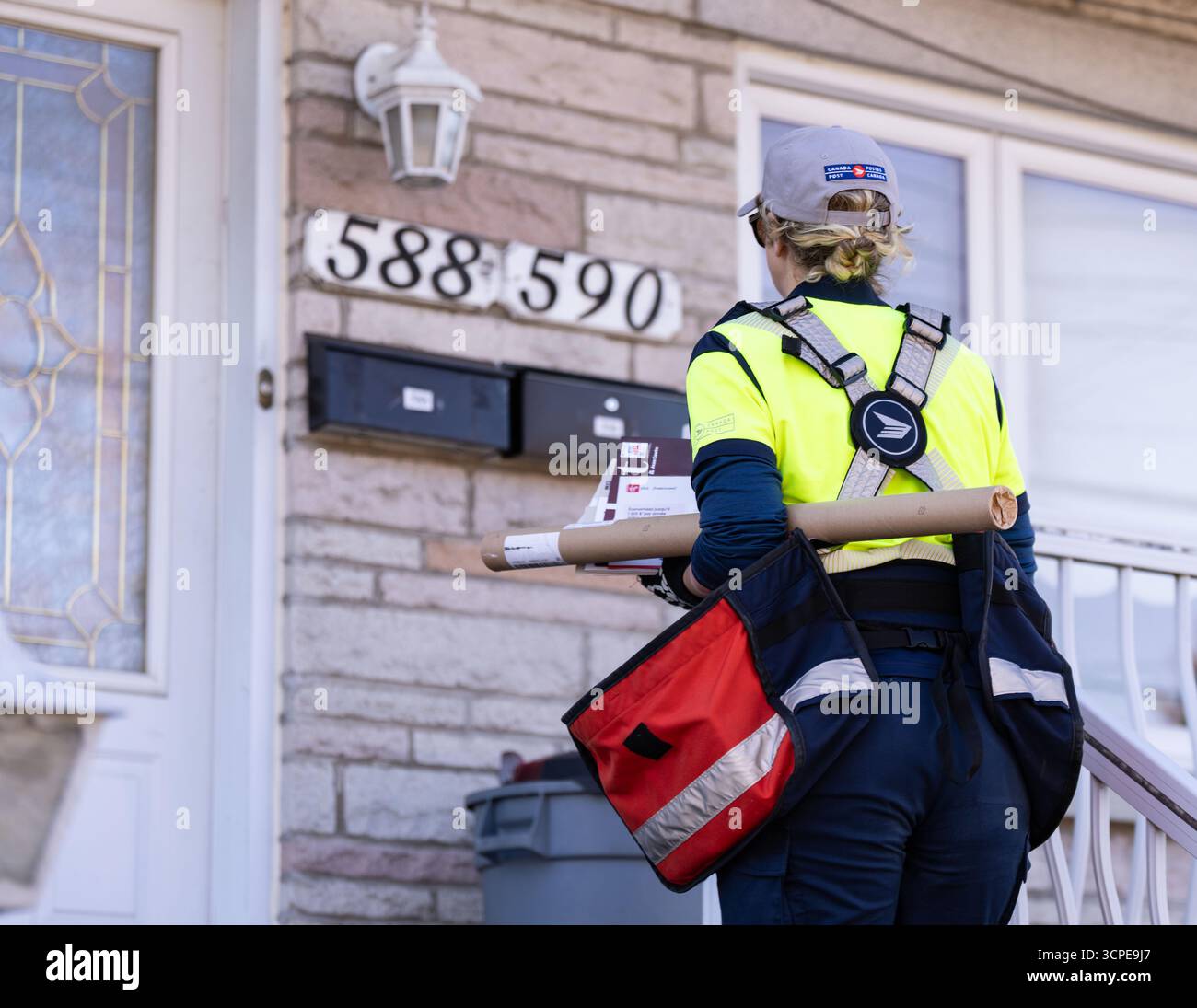 FILE - A Canada Post mail carrier delivers mail and packages on their ...
