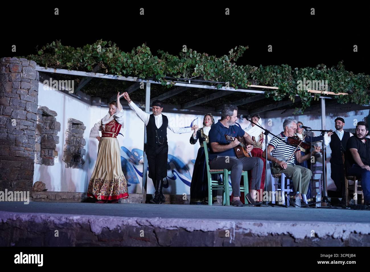Men and women in traditional Cretan costumes dance to the rhythm of ...