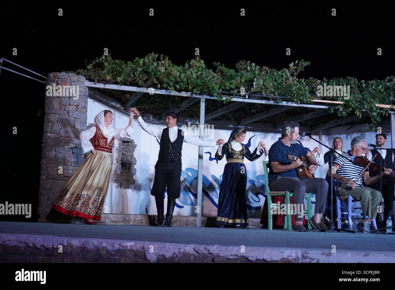 Men and women in traditional Cretan costumes dance to the rhythm of ...