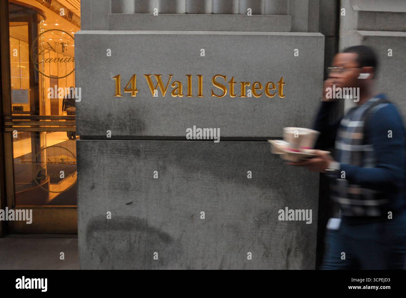 A person walks past a sign for a building at 14 Wall Street in the Financial District in ...