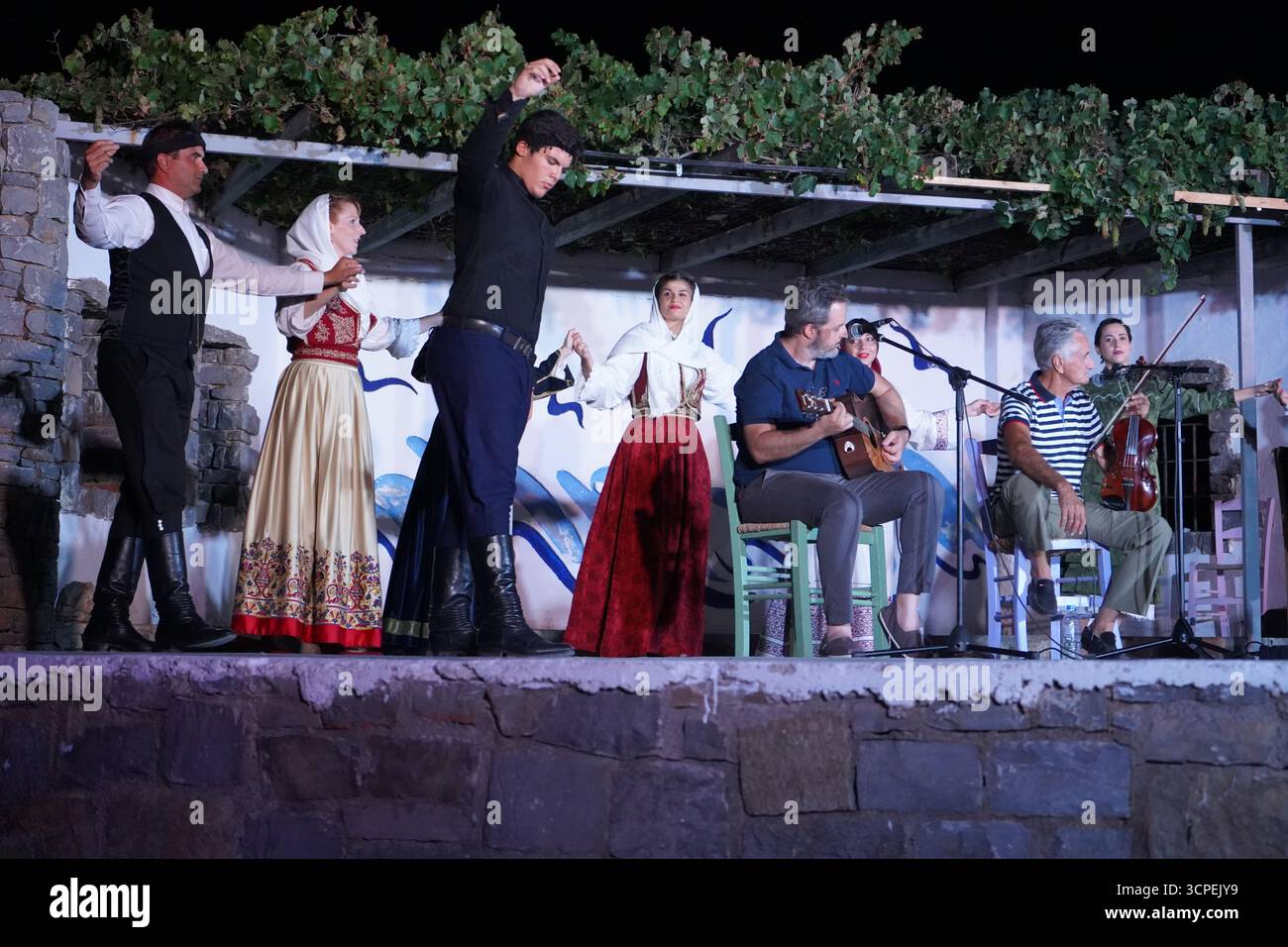 Men and women in traditional Cretan costumes dance to the rhythm of ...