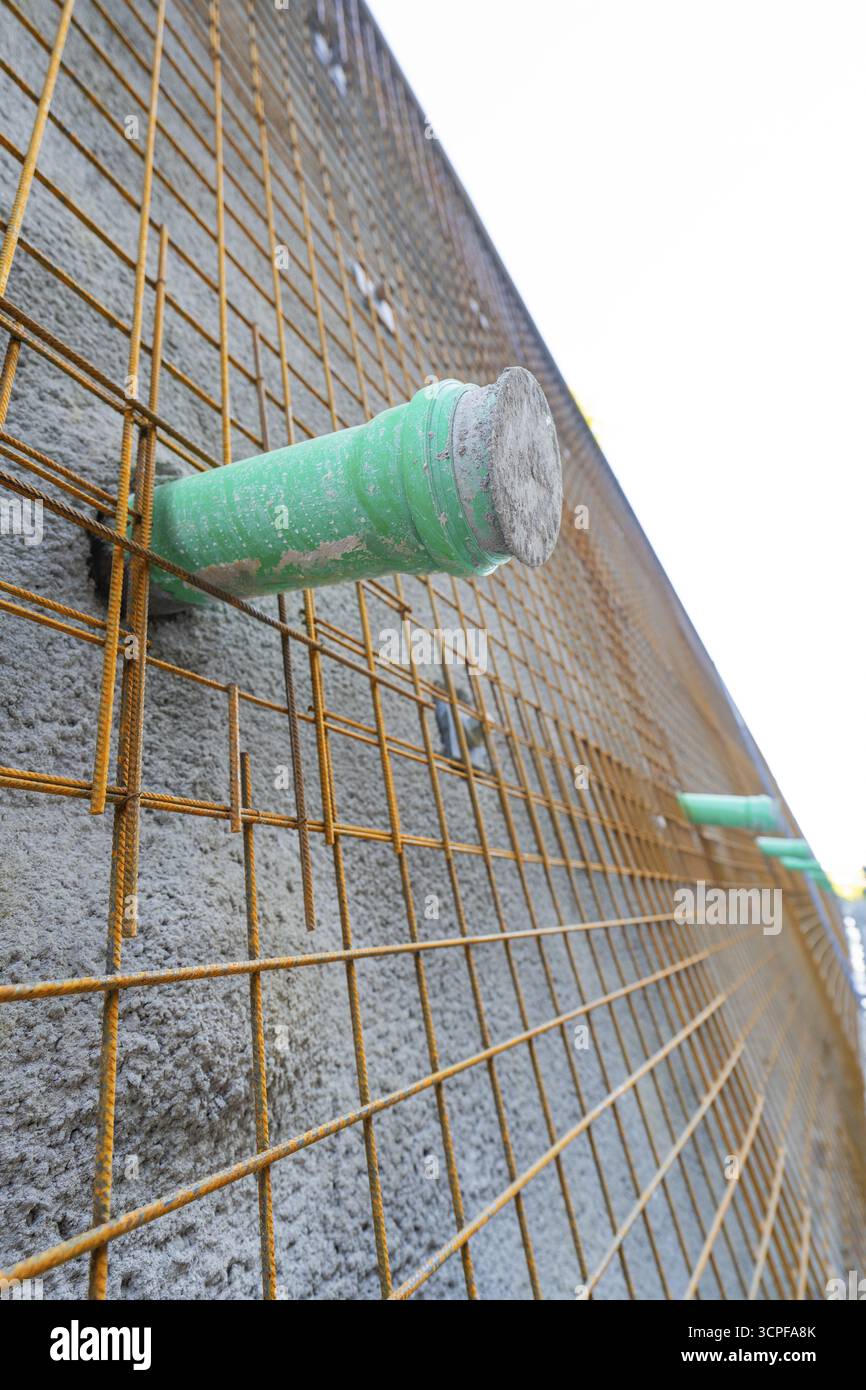 Close-up of a concrete wall with wire mesh and green pipes, Hermann ...