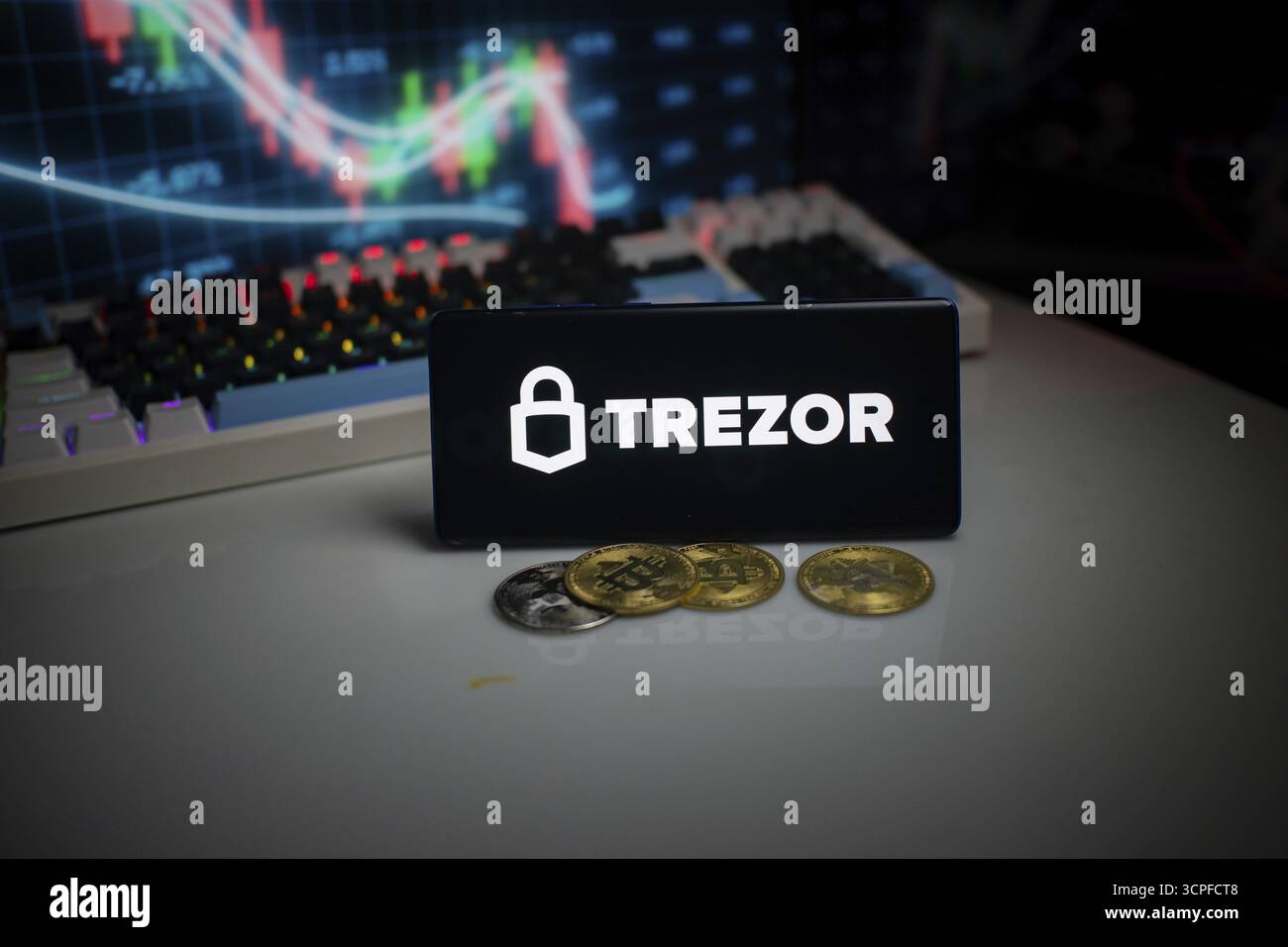 Phone shows Trezor logo with crypto coins and illuminated trading ...