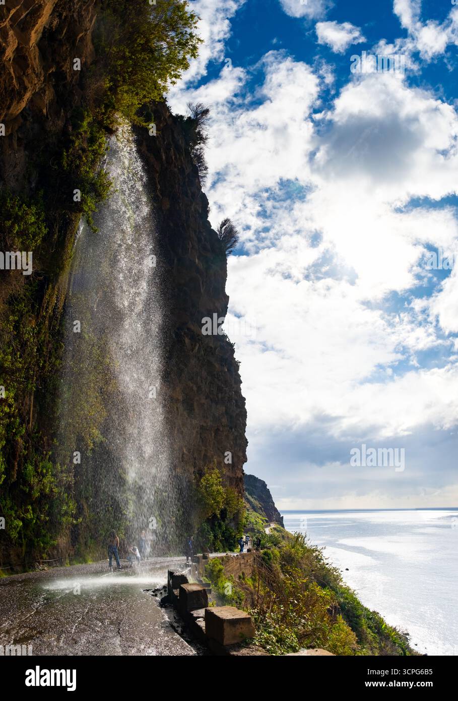 Cascata dos Anjos waterfall flows dramatically over a coastal road in ...