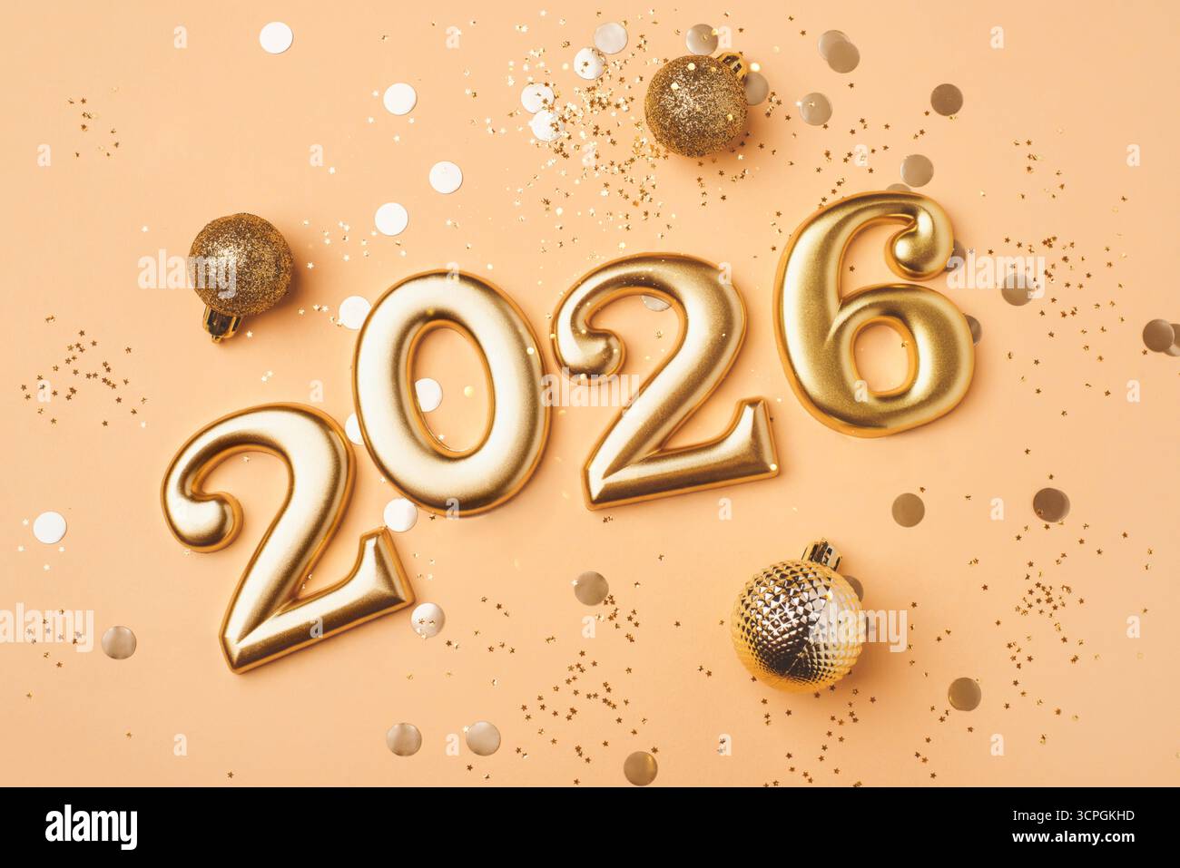 Golden 2026 on a peach color background with confetti and bokeh lights. Happy New Year 2026 is ...