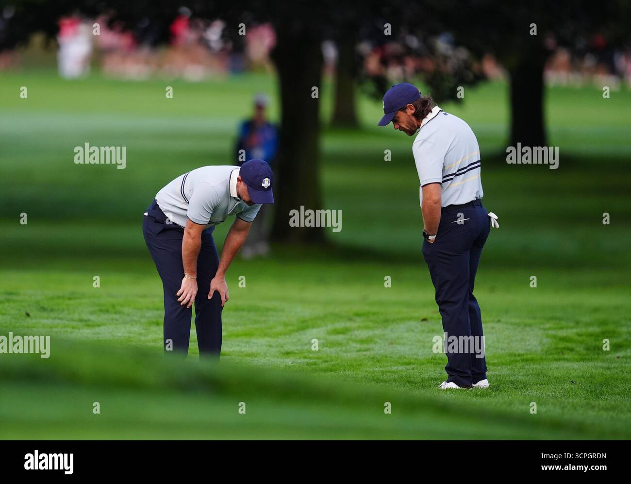 Tommy Fleetwood and Rory McIlroy of Team Europe look at the lay of the ...