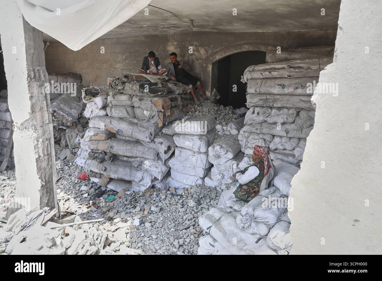 Yemenis sit inside a damaged store following Israeli airstrikes, in ...