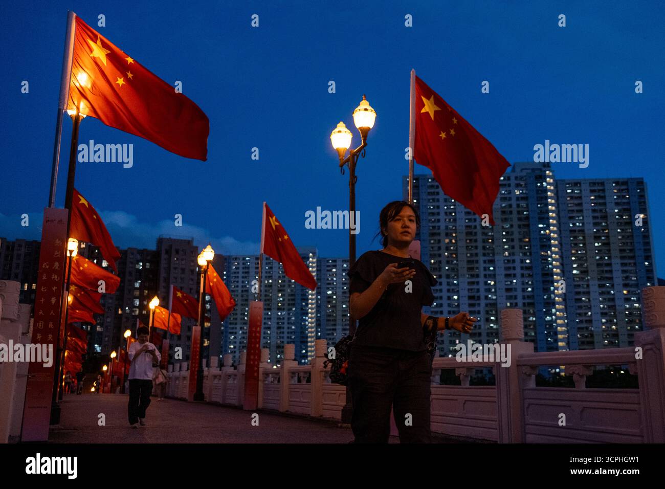 People walking on a bridge with china national flags on it over Shing Mun River in Sha Tin ...