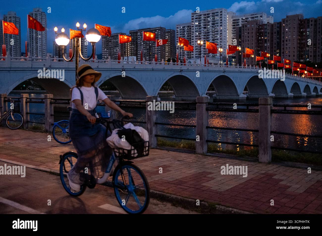 A women cycling pass a bridge with china national flags on it over ...