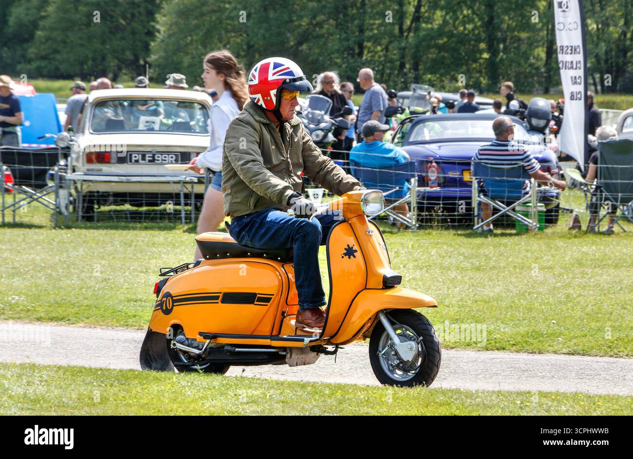 A mod rider on a vintage orange Lambretta scooter wearing a Union Jack ...