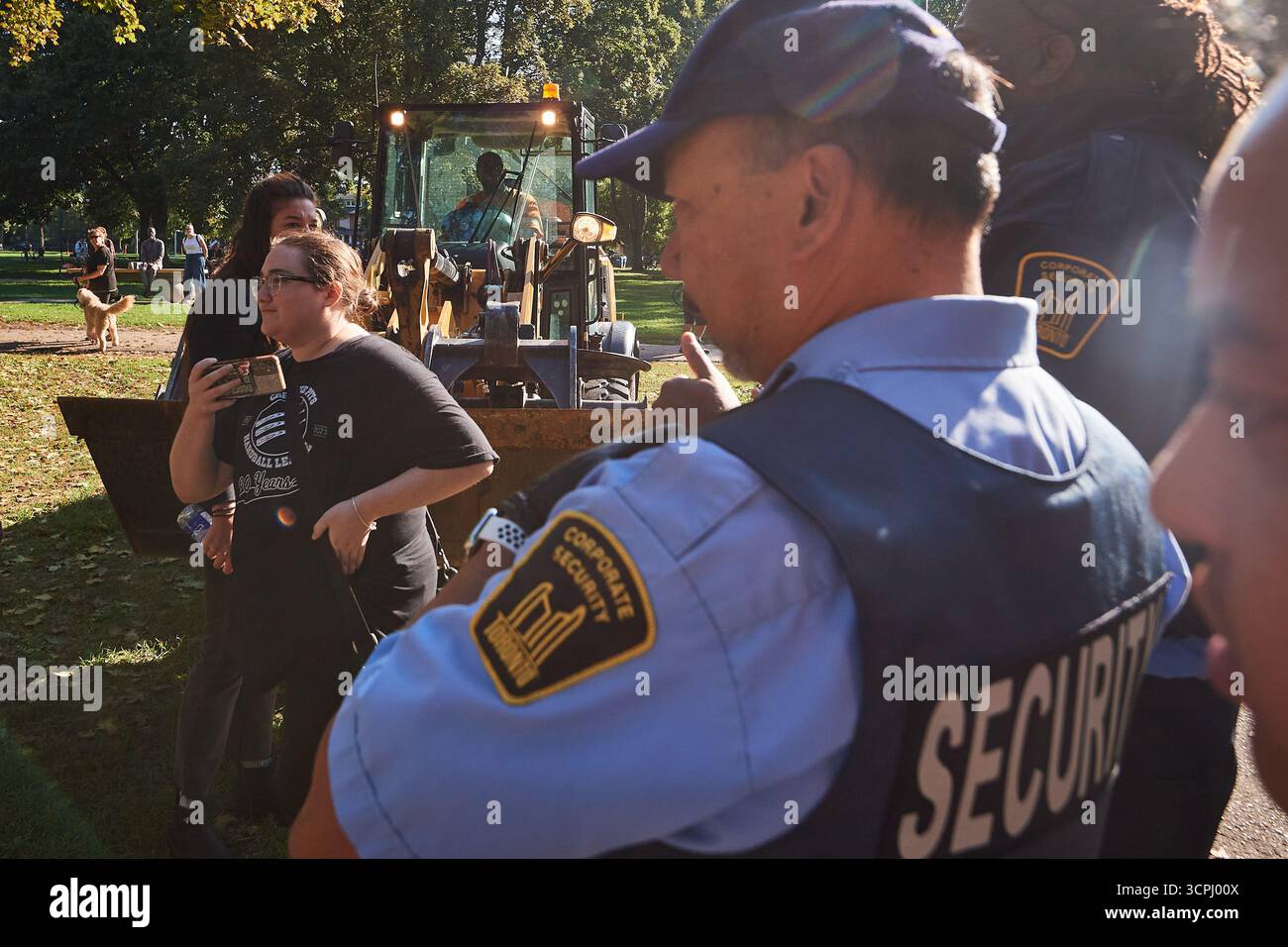 Security and police stand by as workers bring a front-loader truck to ...