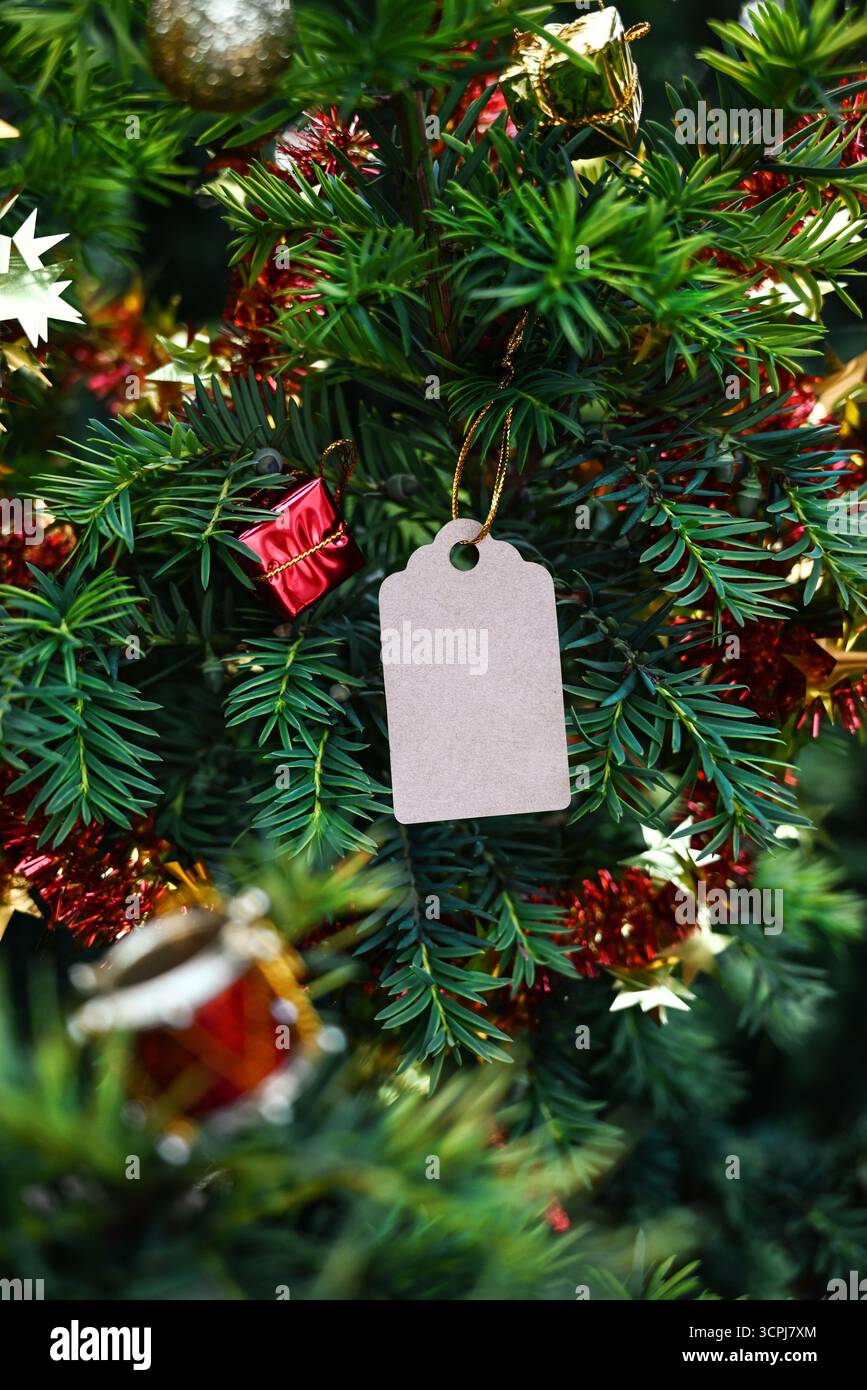 Close-up of a kraft paper tag on a festive Christmas tree with red and ...