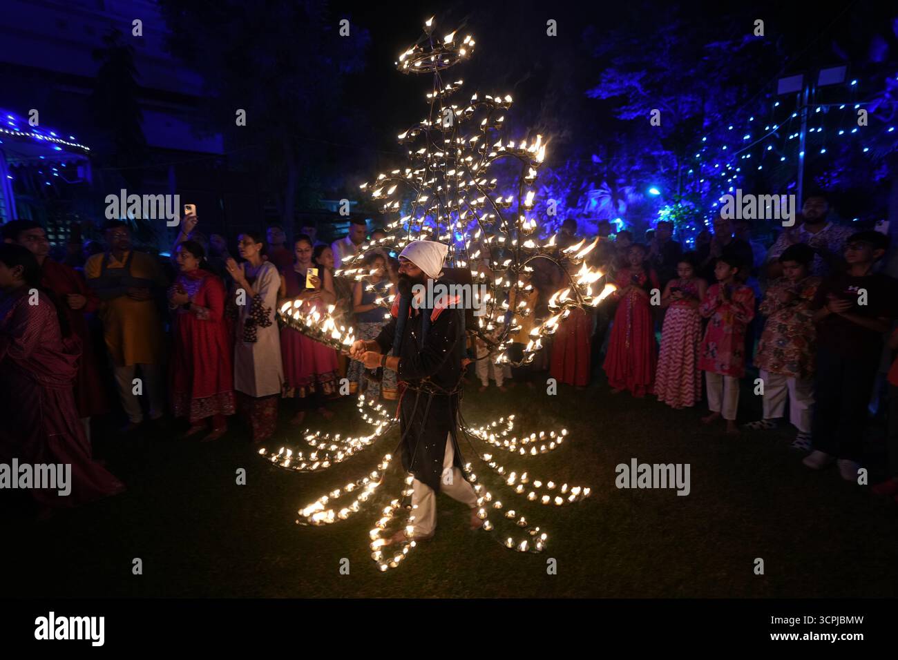 A man performs Aarti rituals wearing a framed costume decorated with ...