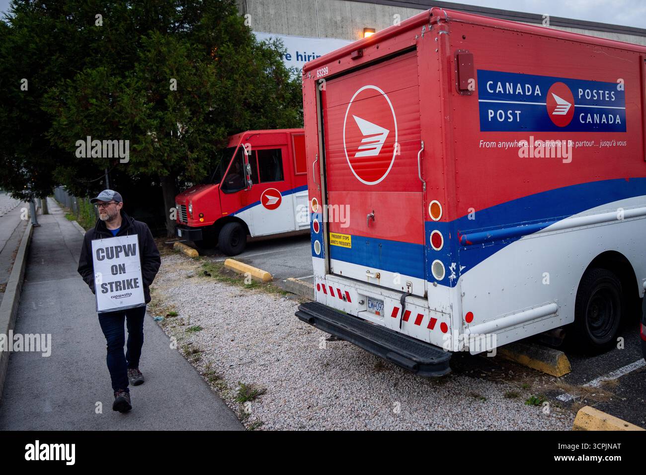 A member of the Canadian Union of Postal Workers pickets outside of a ...