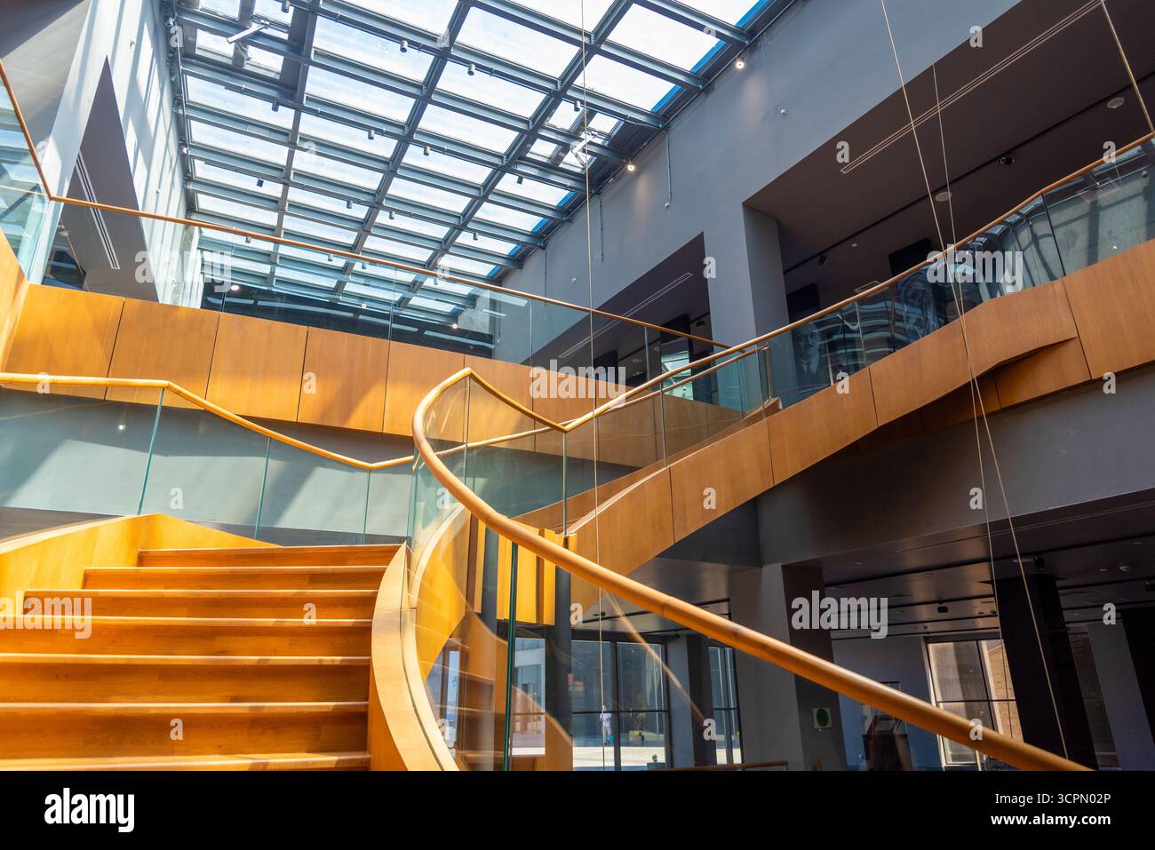 Spacious atrium showcases a contemporary spiral staircase with wooden ...