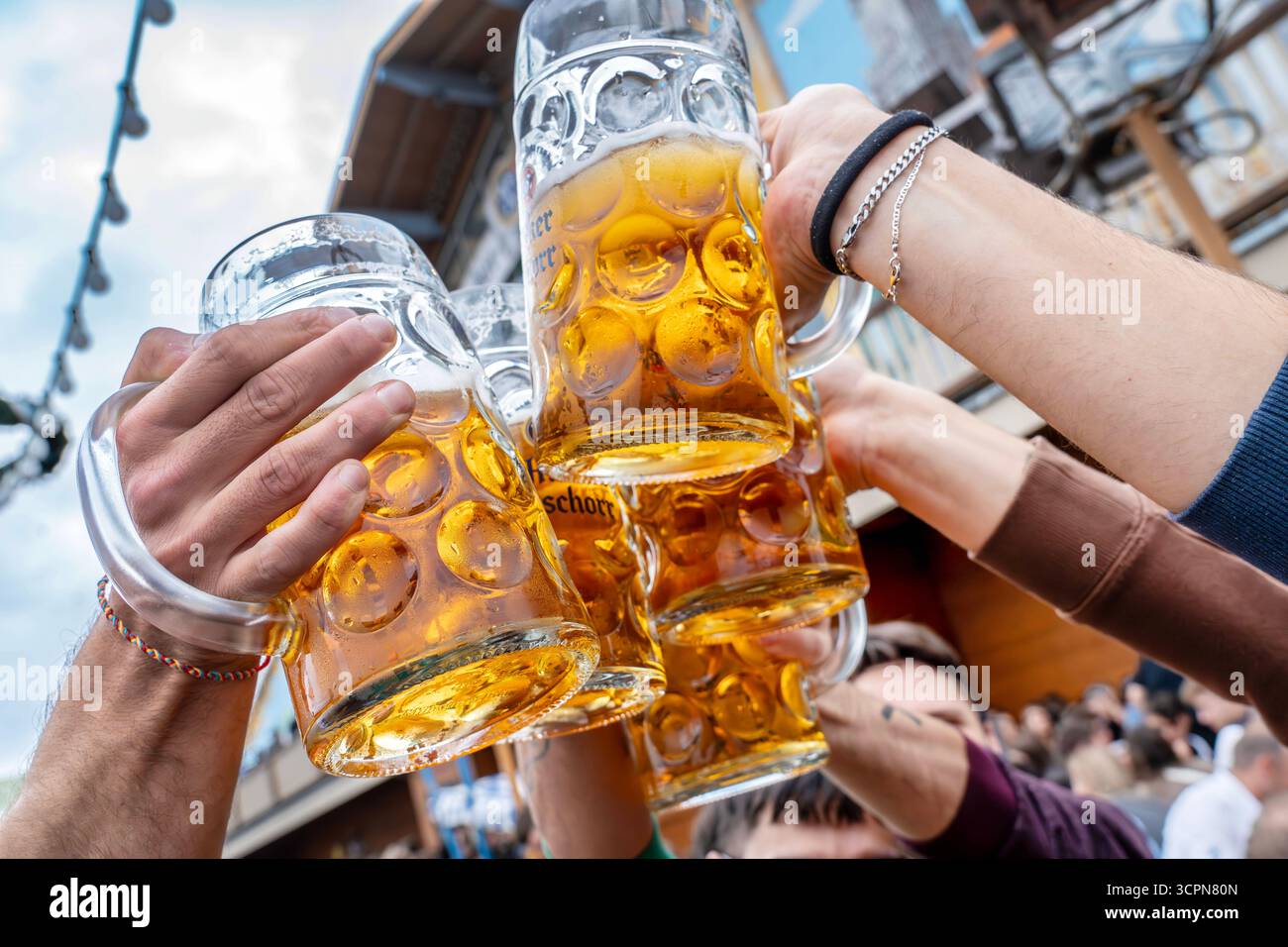 Oktoberfest, durstige Besucher trinken ihre Mass Bier, prosten sich zu ...