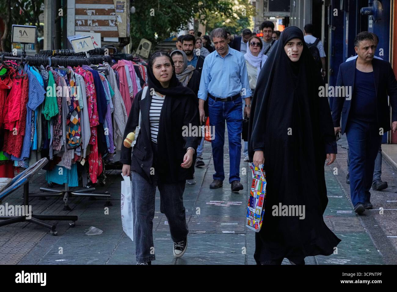 People walk on a sidewalk at the Enqelab-e-Eslami (Islamic Revolution ...