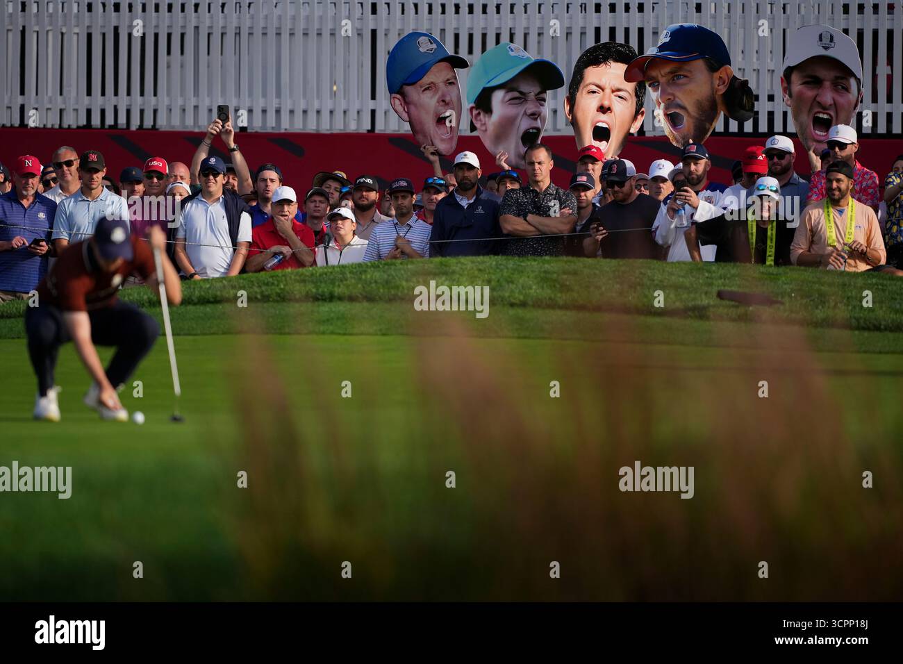 Fans hold up photos as Europe's Matthew Fitzpatrick lines up a putt on ...