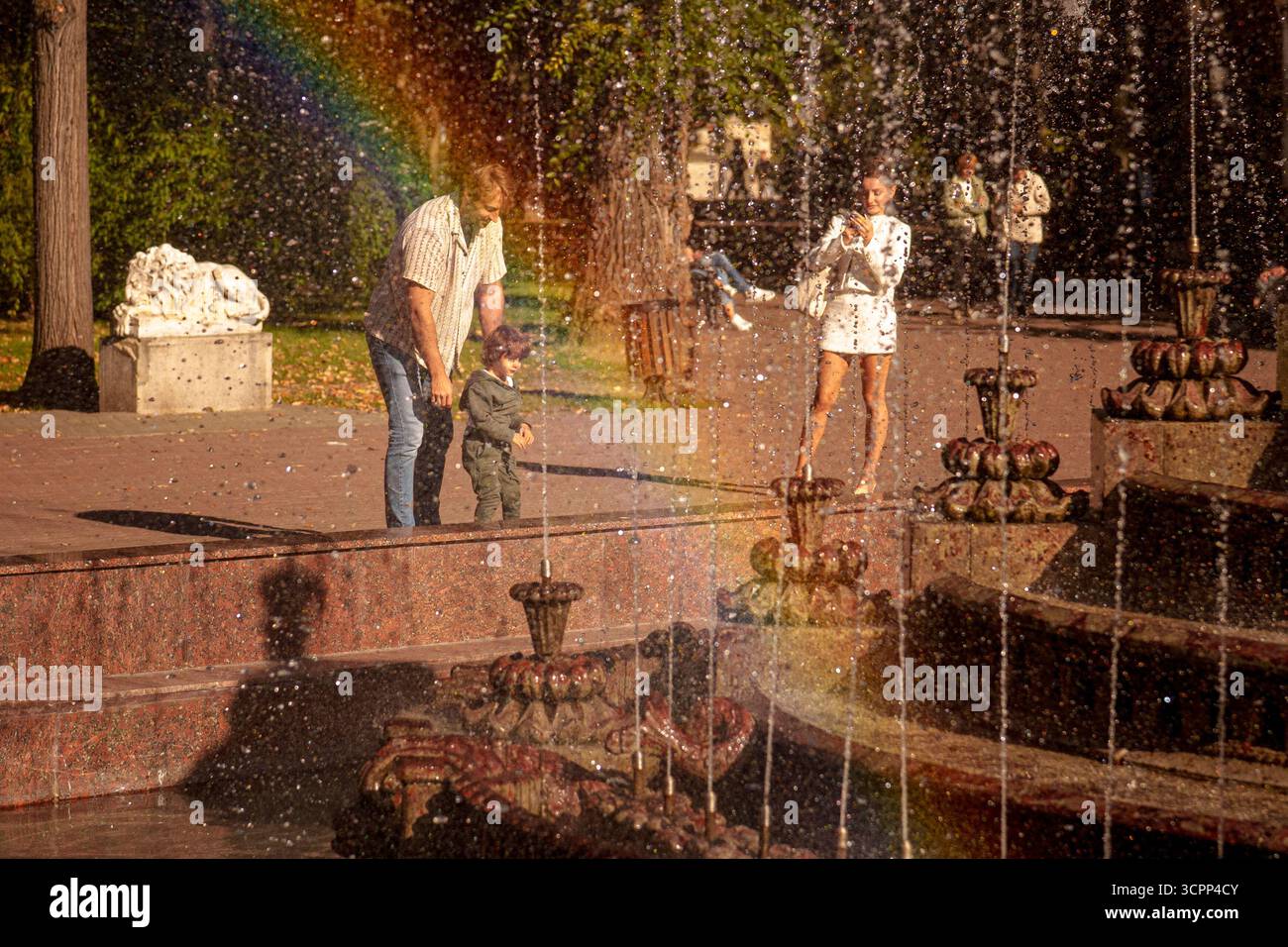 A man and a child watch a fountain in a park in downtown Chisinau ...