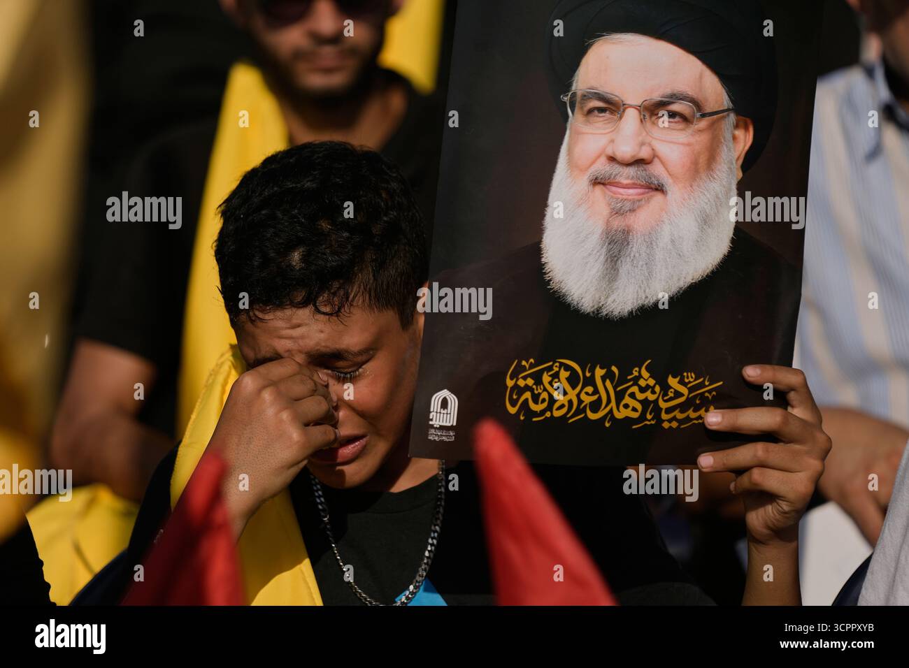 A Hezbollah supporter weeps as he hold an image of Hezbollah leader ...