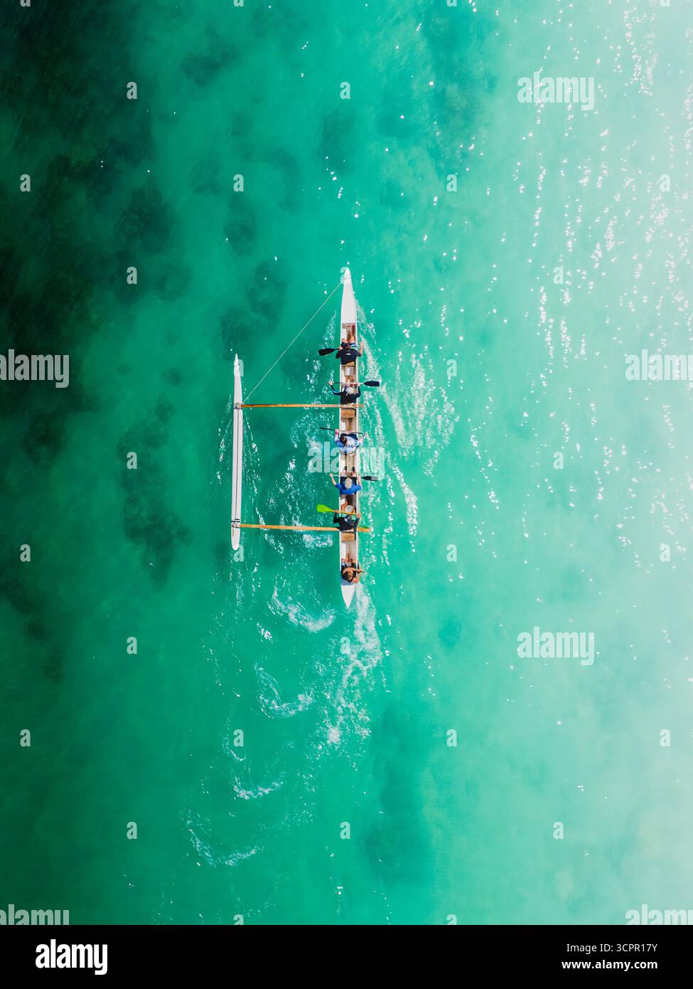 Aerial view of a canoe slices through the turquoise waters, propelled ...