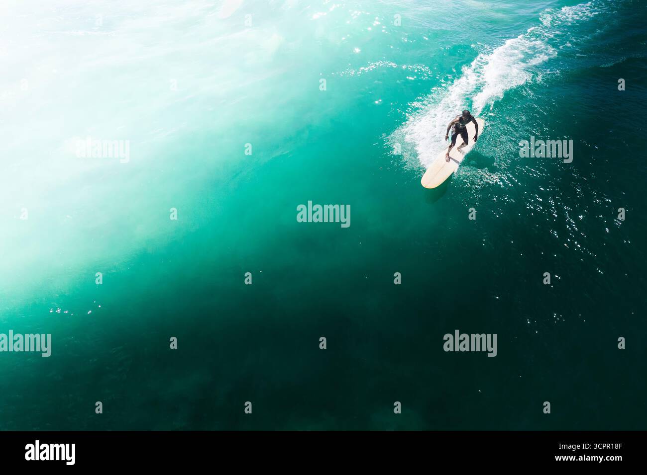 Aerial view of a surfer riding a vibrant turquoise wave, a dance of ...