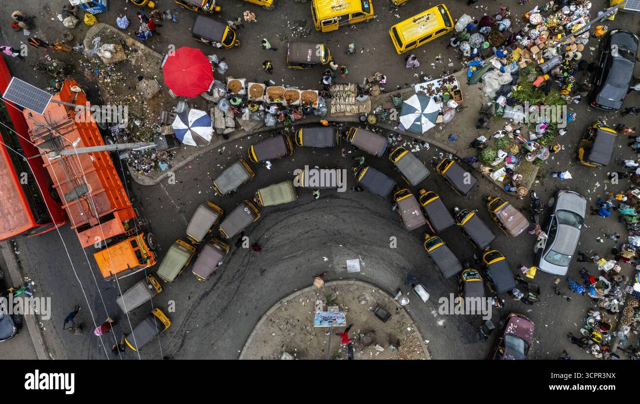 Aerial view of yellow and brown danfo buses and Keke Napeps converge in ...