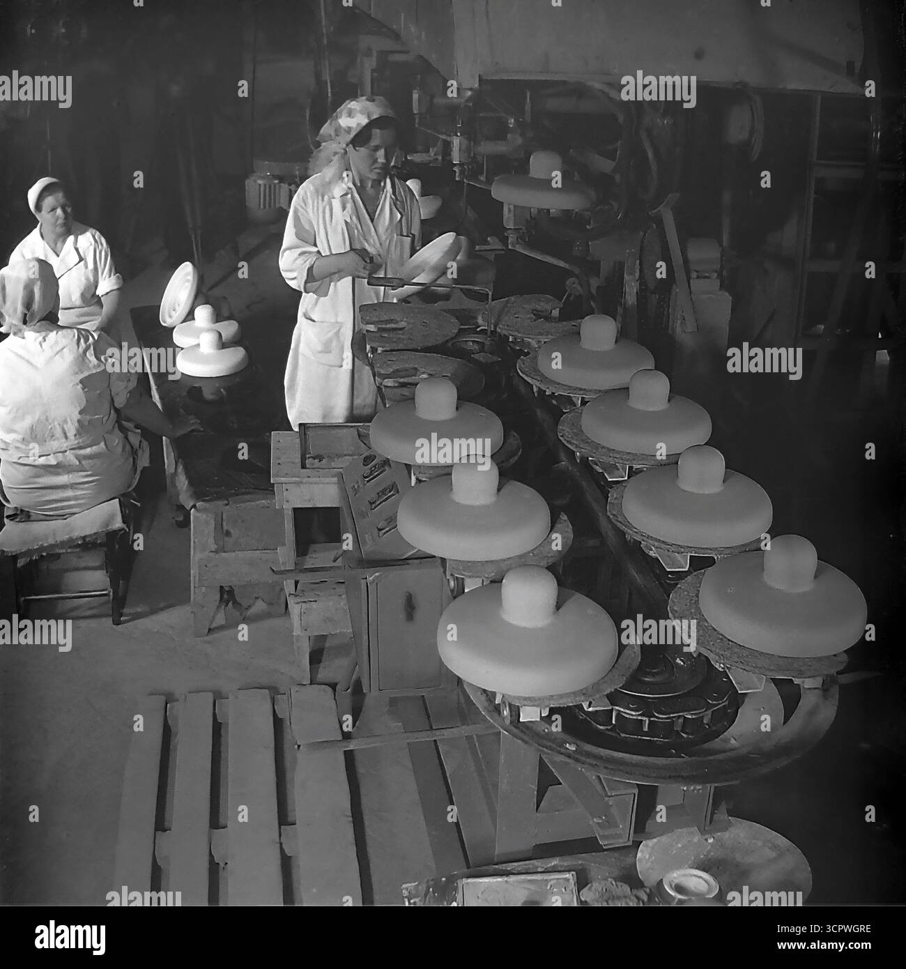 A brigade of female workers in white coats works on a semi-automated ...