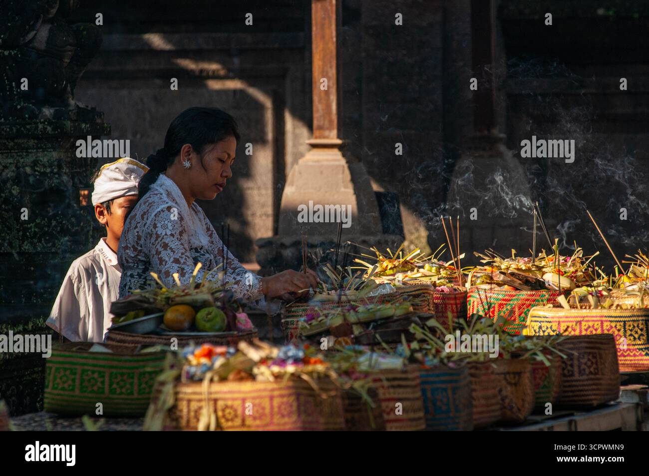 A Balinese woman with offerings & incense, dressed in traditional ...