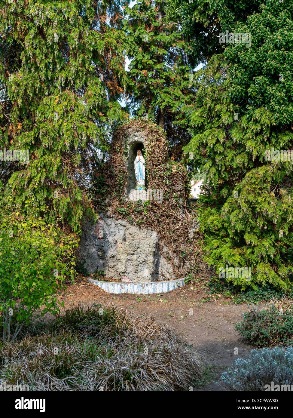 Outdoor grotto with statue of the Virgin Mary near the church and ...