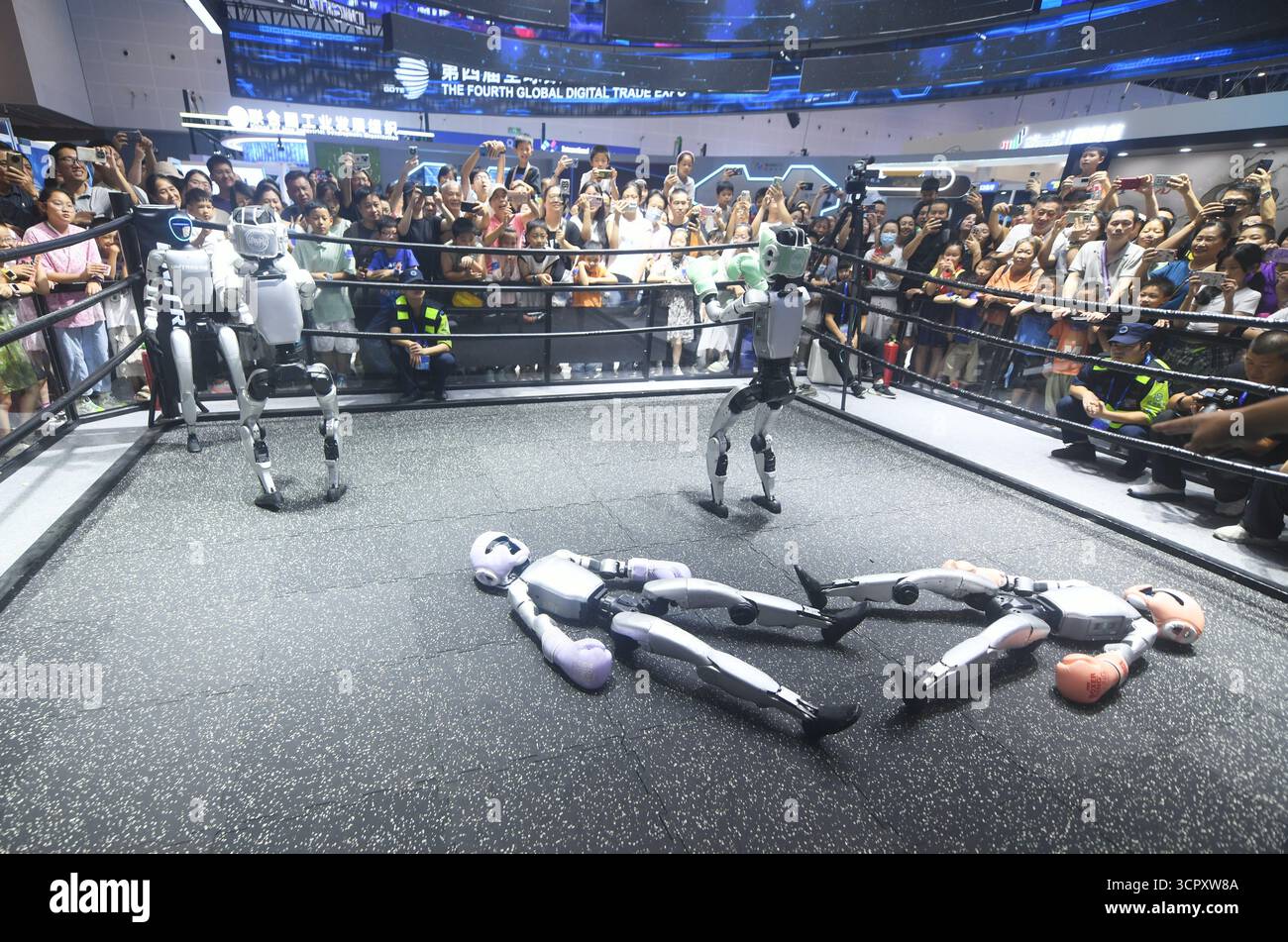 People watch four Unitree humanoids fighting in a boxing ring during a ...