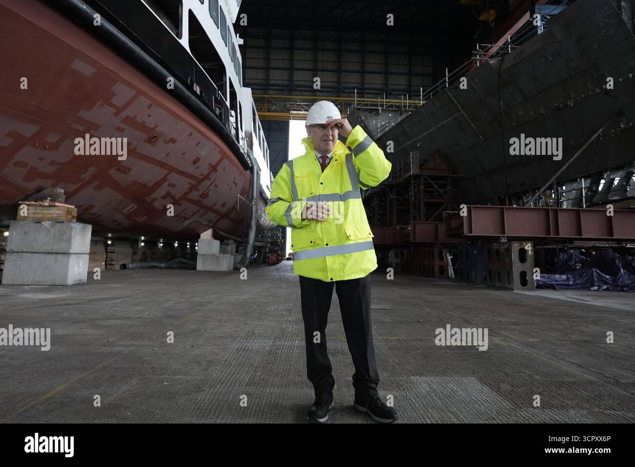 Defence Secretary John Healey standing in between a Mersey Ferry (left ...
