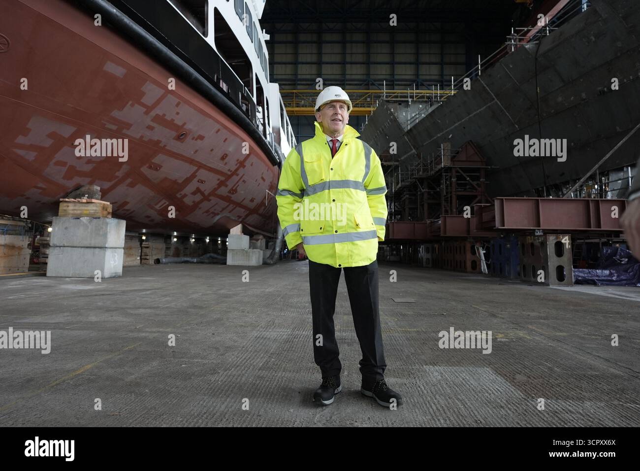 Defence Secretary John Healey standing in between a Mersey Ferry (left ...