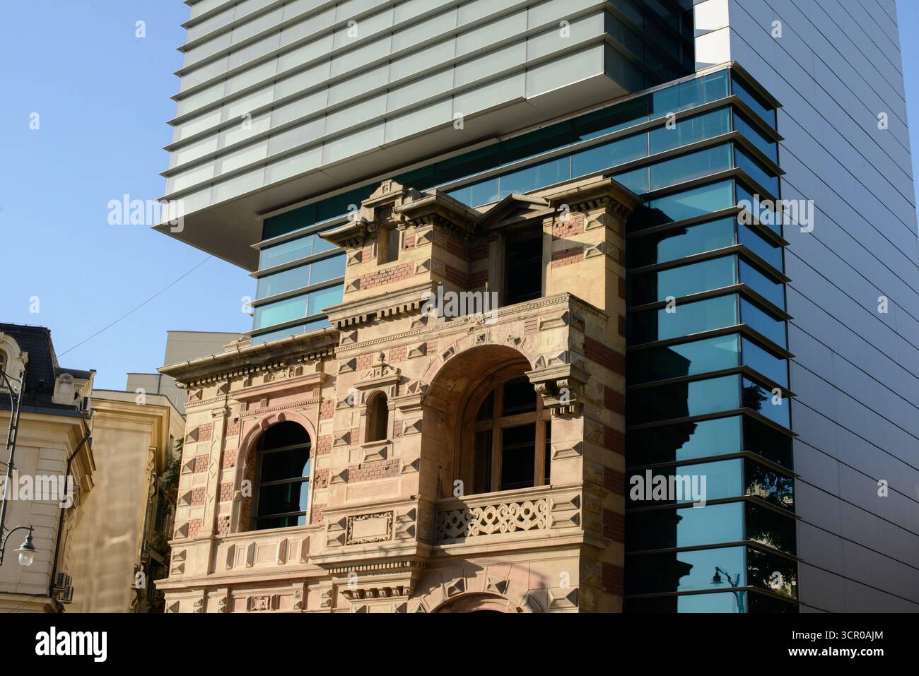 A historic stone facade integrated into a modern glass tower in central ...