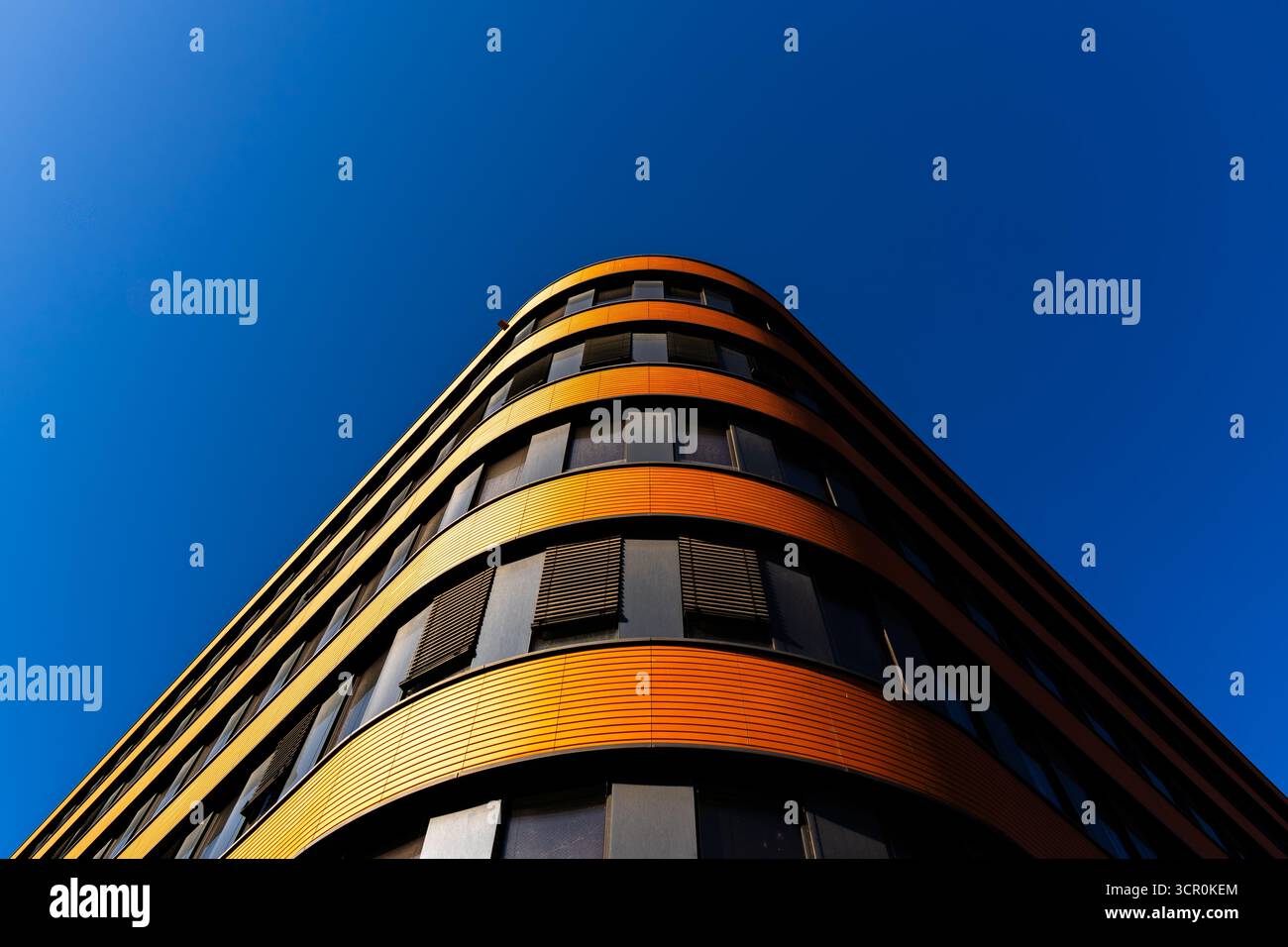 Modern curved building facade with orange cladding and dark windows ...