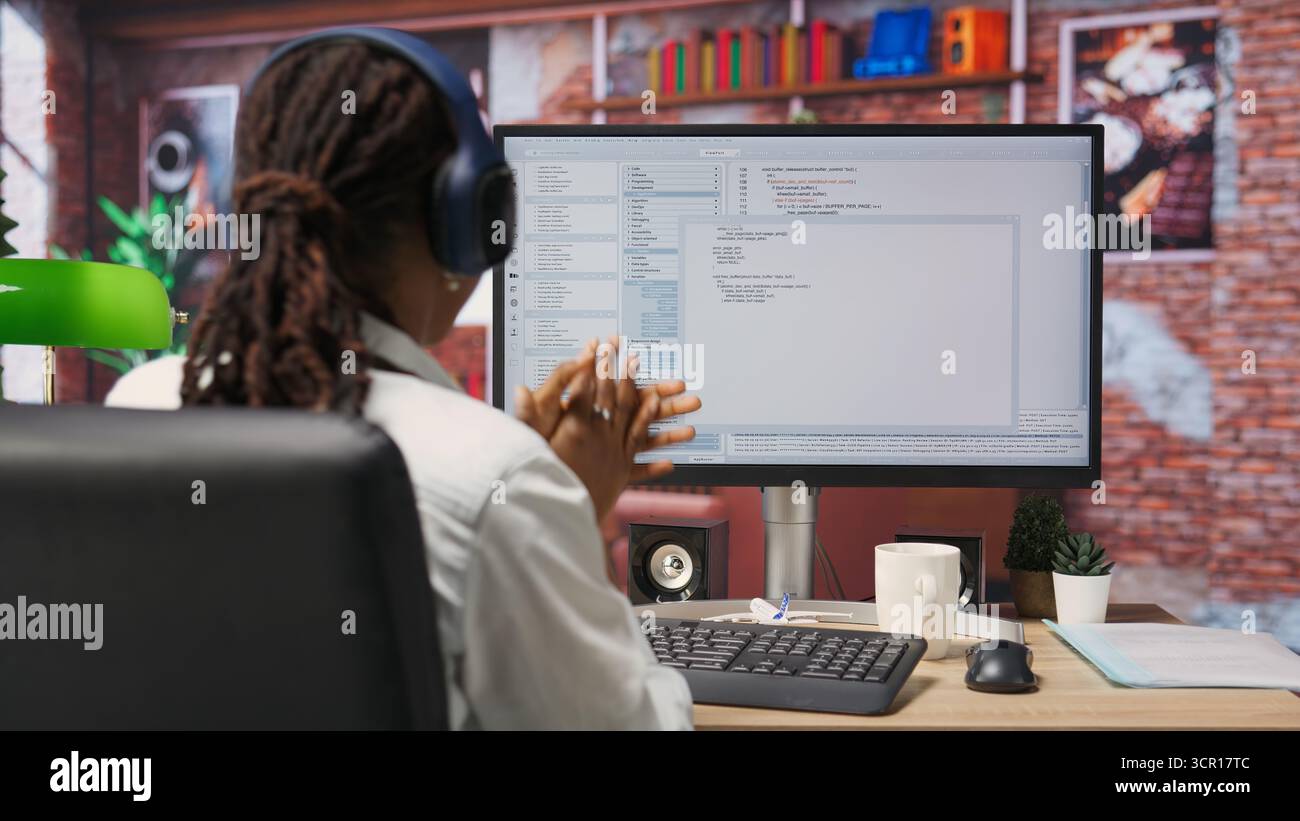 Excited programmer wearing headphones testing code on PC, clapping ...