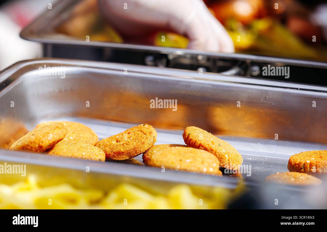 Golden falafel patties in stainless steel tray at outdoor food market ...