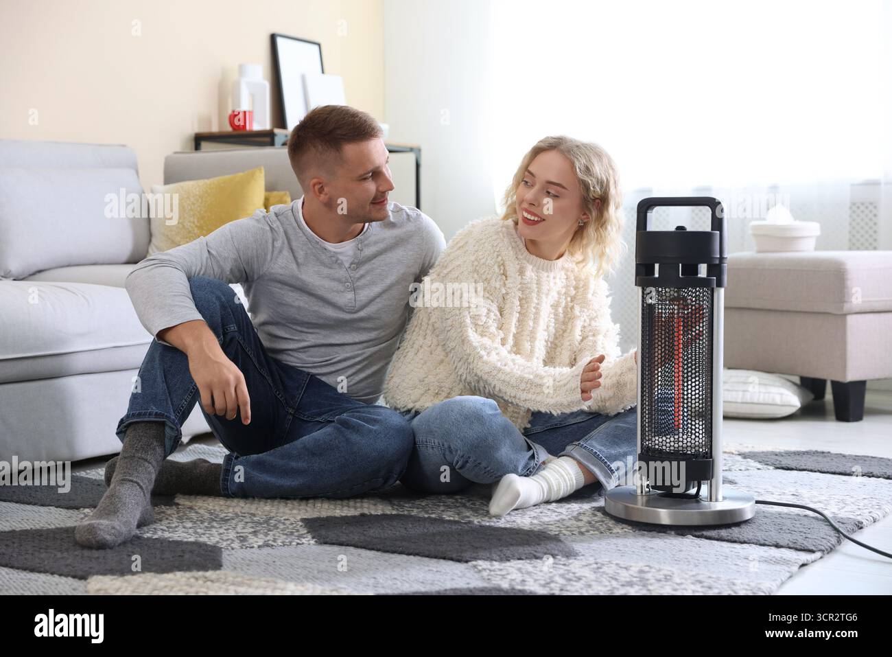 Happy couple near electric heater on floor at home Stock Photo - Alamy