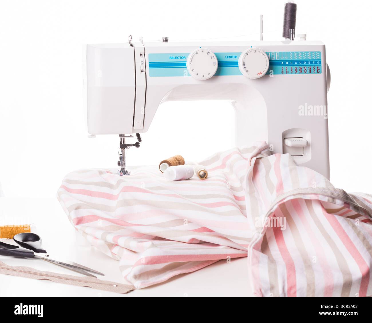 Sewing machine in use with striped fabric and sewing tools arranged ...