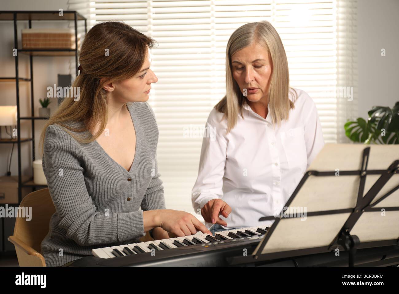 Tutor teaching woman to play piano indoors Stock Photo - Alamy