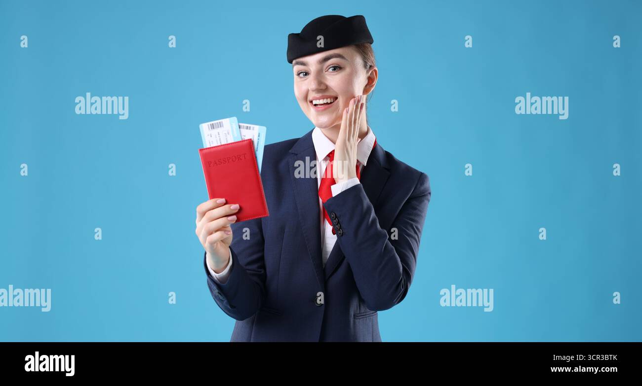Smiling stewardess with passport and tickets on light blue background ...