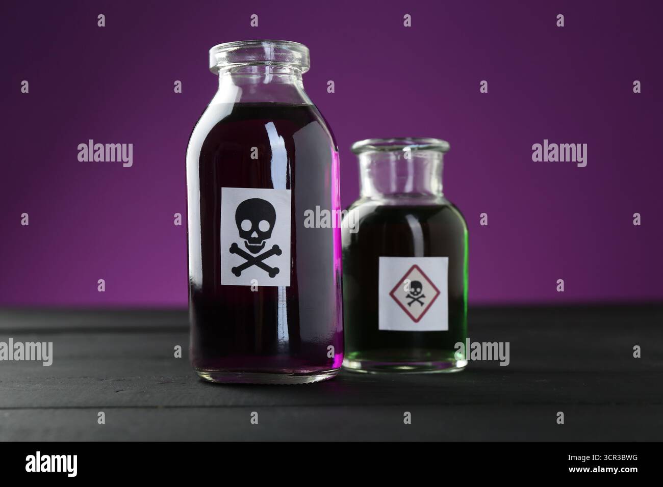 Bottles of poison with warning signs on black wooden table against ...
