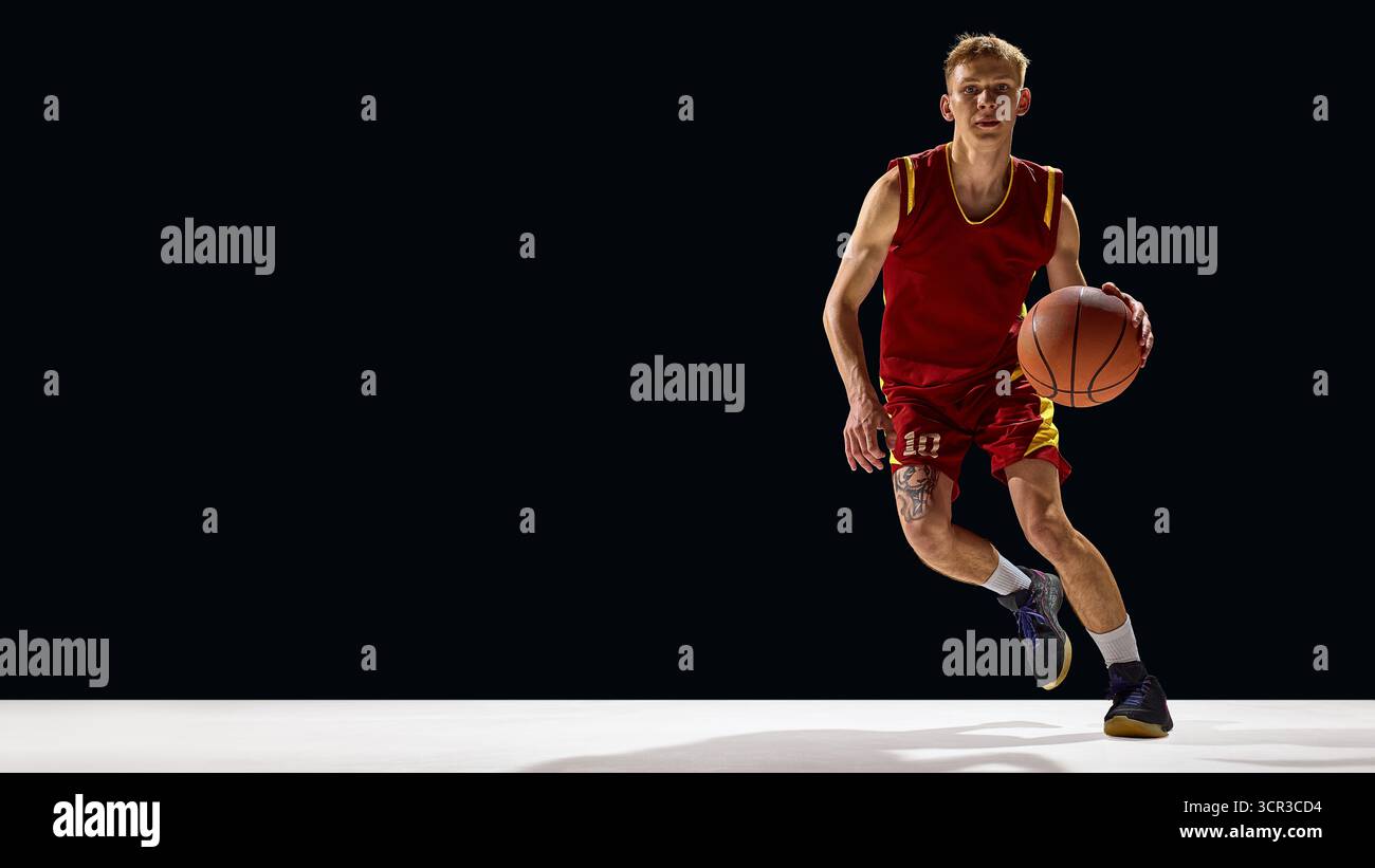 Basketball player in red uniform dribbling with sharp concentration ...