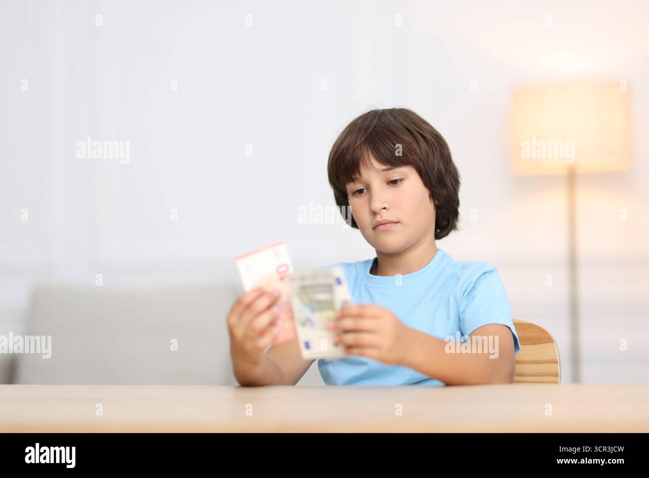 Boy with pocket money at wooden table indoors. Space for text Stock ...