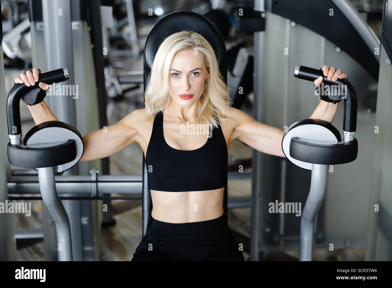 Concentrating on training, a fitness woman works on her pectoral ...