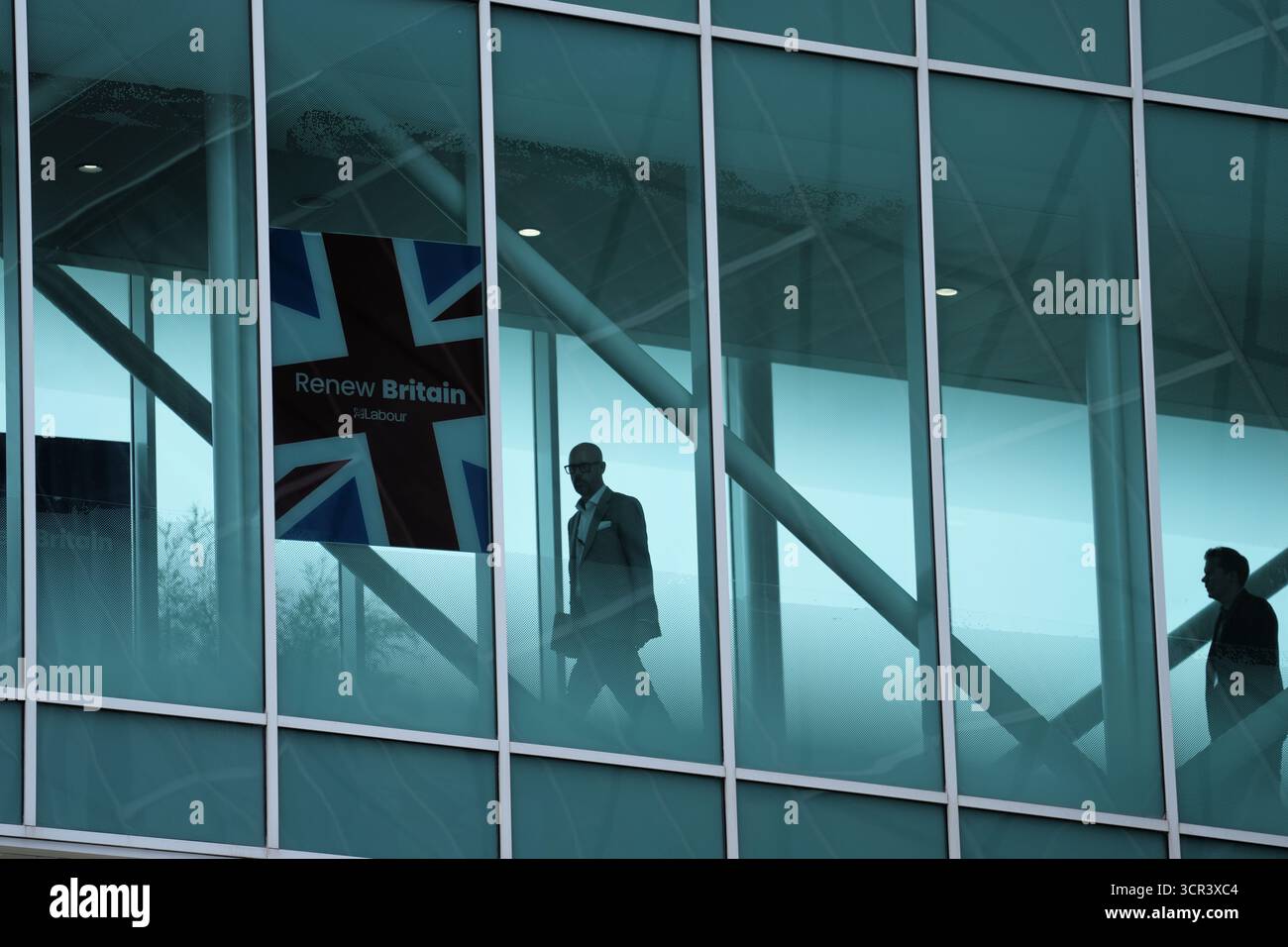 A delegate walks along a corridor pas a large Renew Britain poster ...
